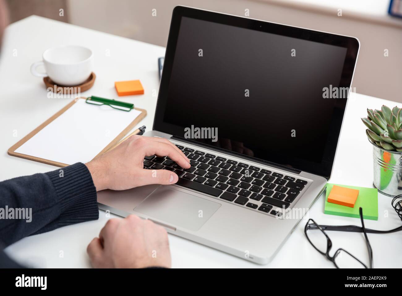 Computer screen mockup. Man working with a black blank screen laptop on ...