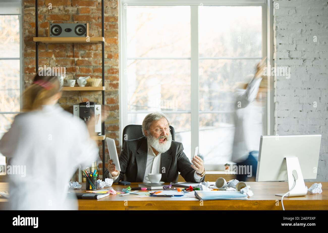 Tired boss resting at his workplace while busy people moving near ...