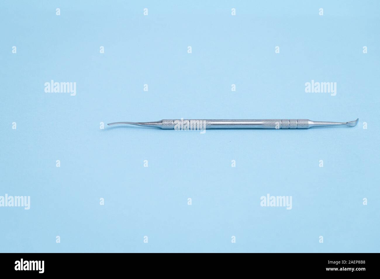 Stainless dental probe laying on light blue background Stock Photo - Alamy