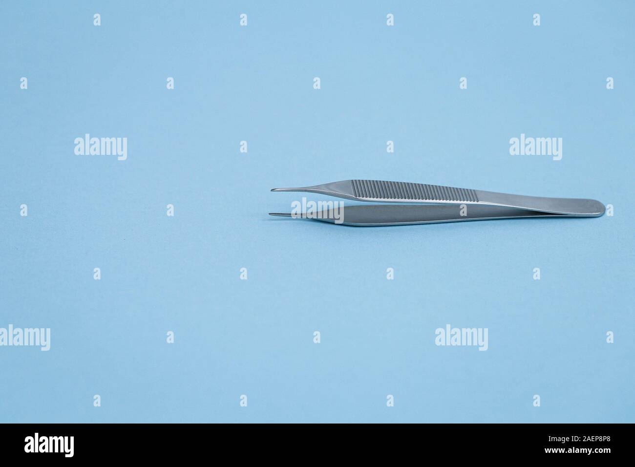 Steel dental tweezers on light blue background Stock Photo - Alamy