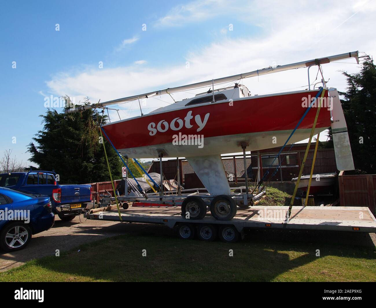 A small racing yacht being transported by road on a flatbed trailer by ...