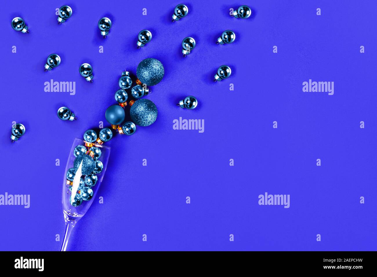 Blue christmas balls in a wine glass on a same color background. Flat ...