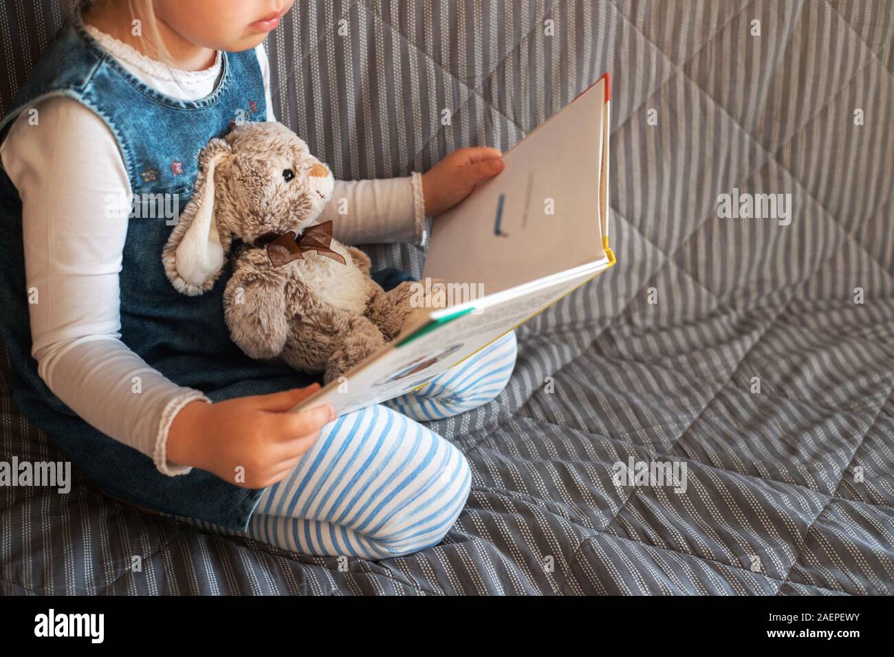 Little girl reading favorite book at home with her toy rabbit Stock ...