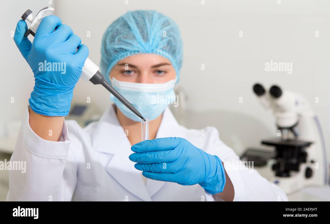 Female scientist dropping samples from big pipette for testing on ...