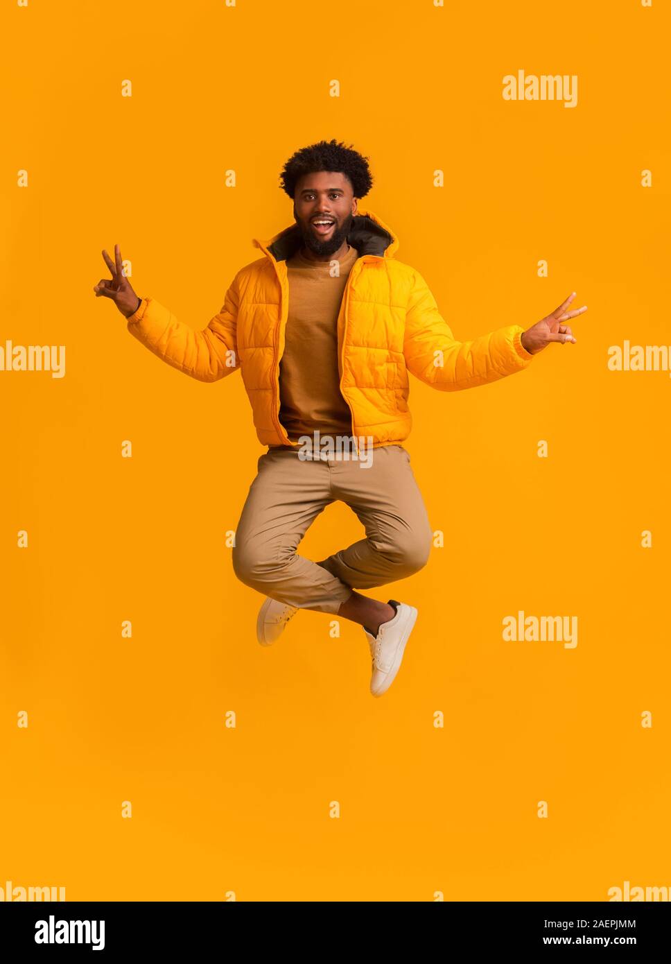 Peaceful winter guy demonstrating peace symbol while jumping Stock ...