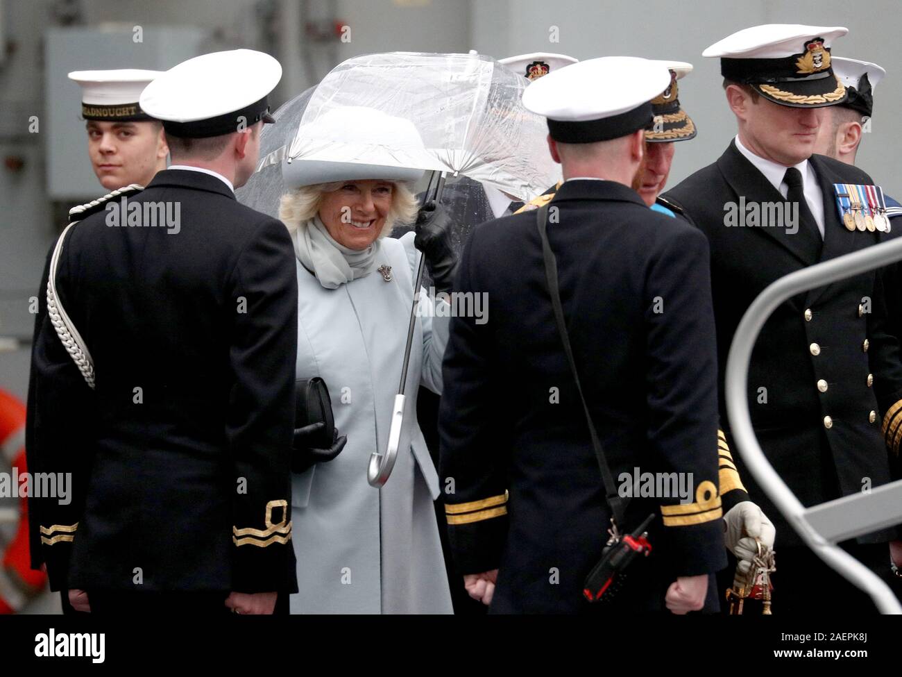 The Duchess of Cornwall uses an umbrella to shelter from the rain as ...