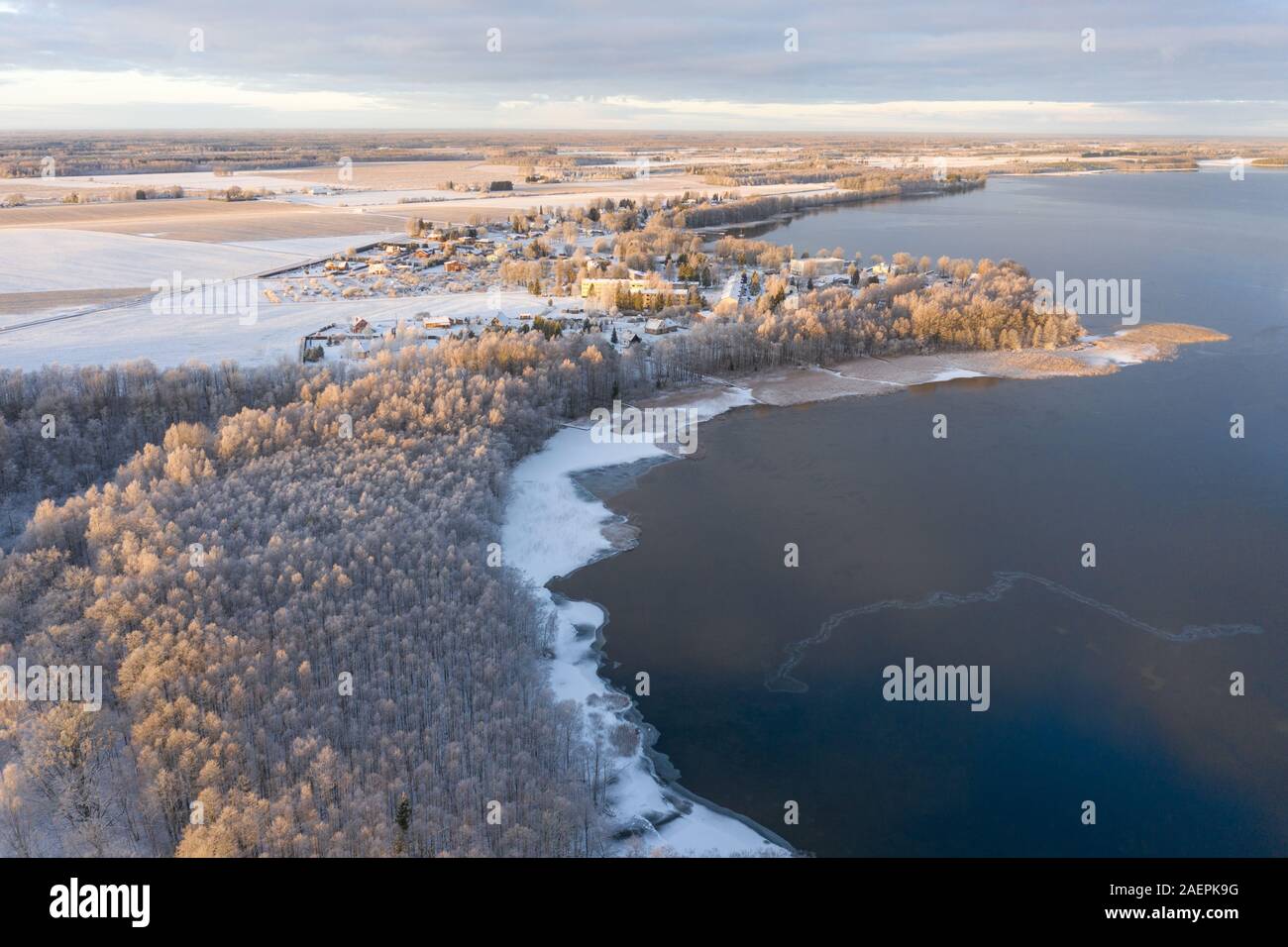 Aerial drone view of a lake coast starting to freeze over in winter ...