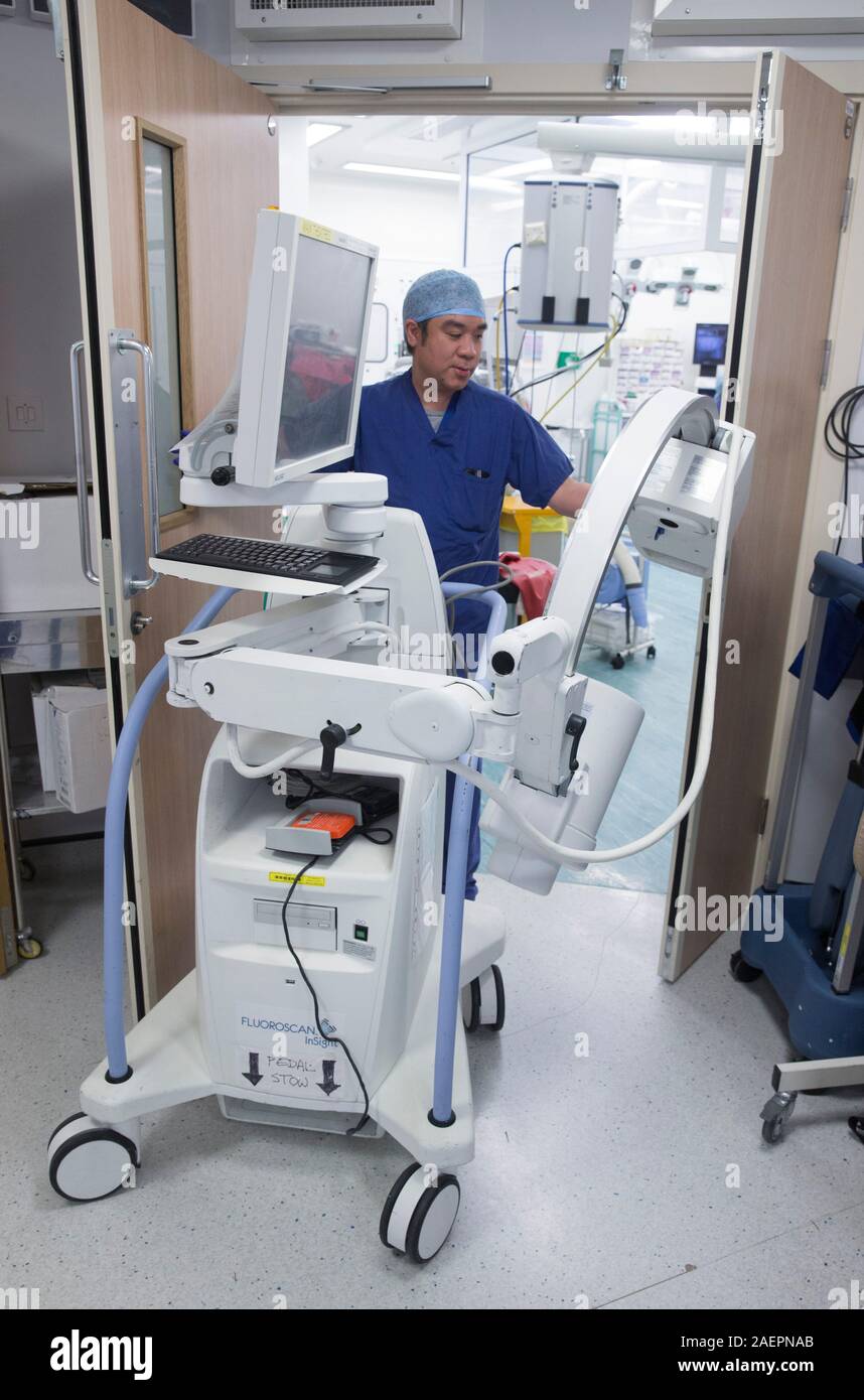 A Nurse in scrubs pulls an X Ray monitor machine into an operating ...