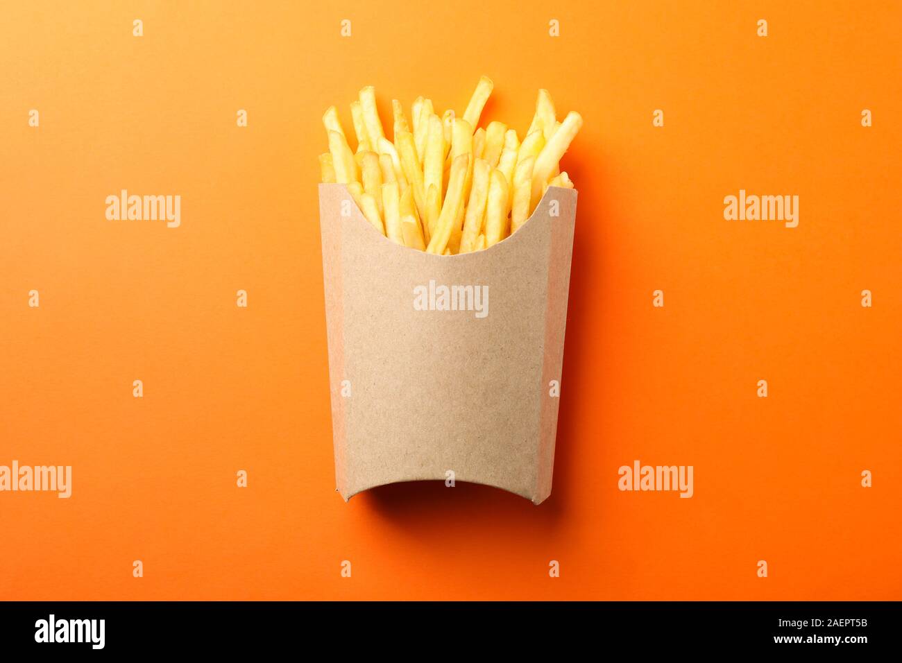 Slices of hot french fries in box on orange background, space for text ...