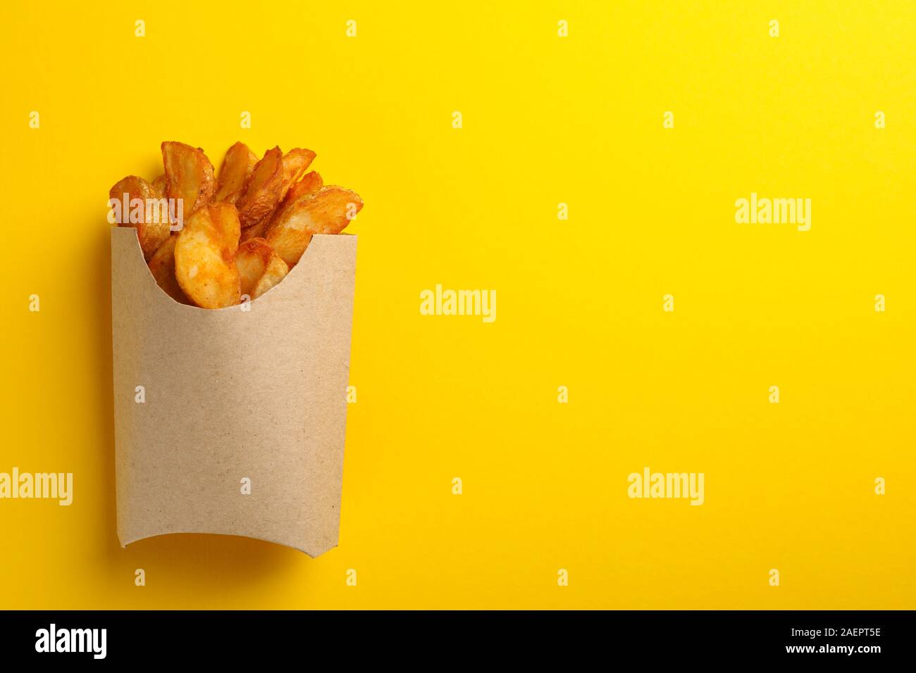 Baked potato wedges in box on yellow background, space for text. Top ...