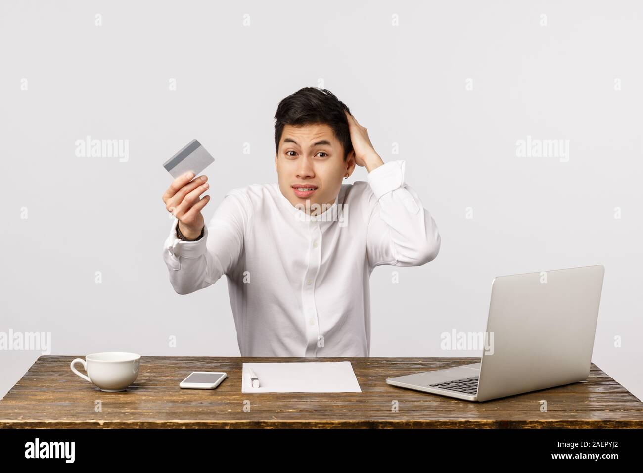 Awkward handsome chinese guy sitting office desk with laptop, documents ...