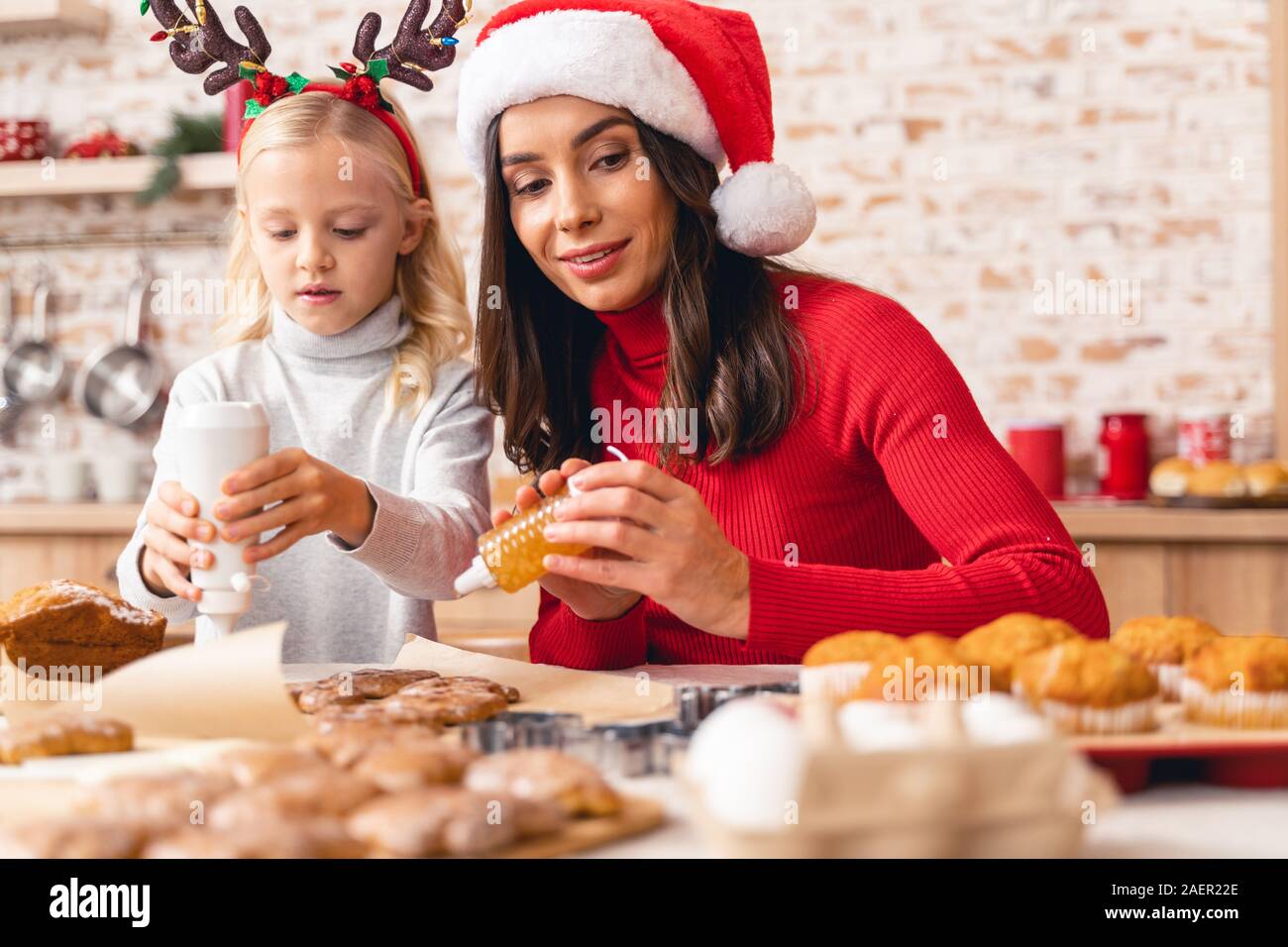 Cute female child helping her pleased mother Stock Photo - Alamy