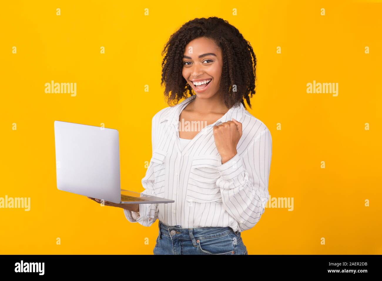 Excited black employee feeling ecstatic holding laptop Stock Photo - Alamy