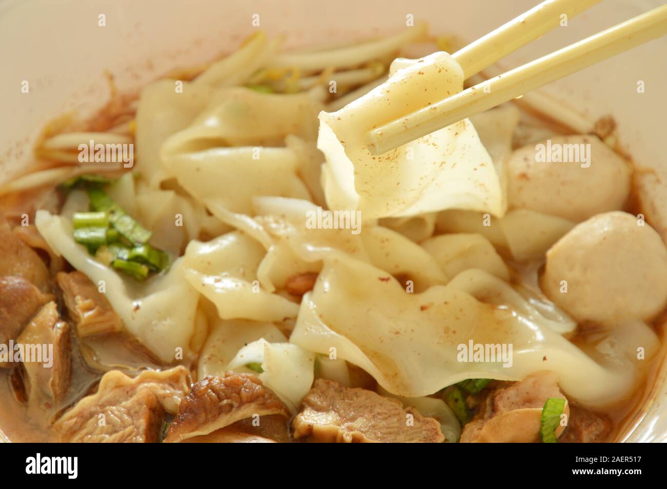 large rice noodle with braised pork in soup picking by chopstick Stock ...