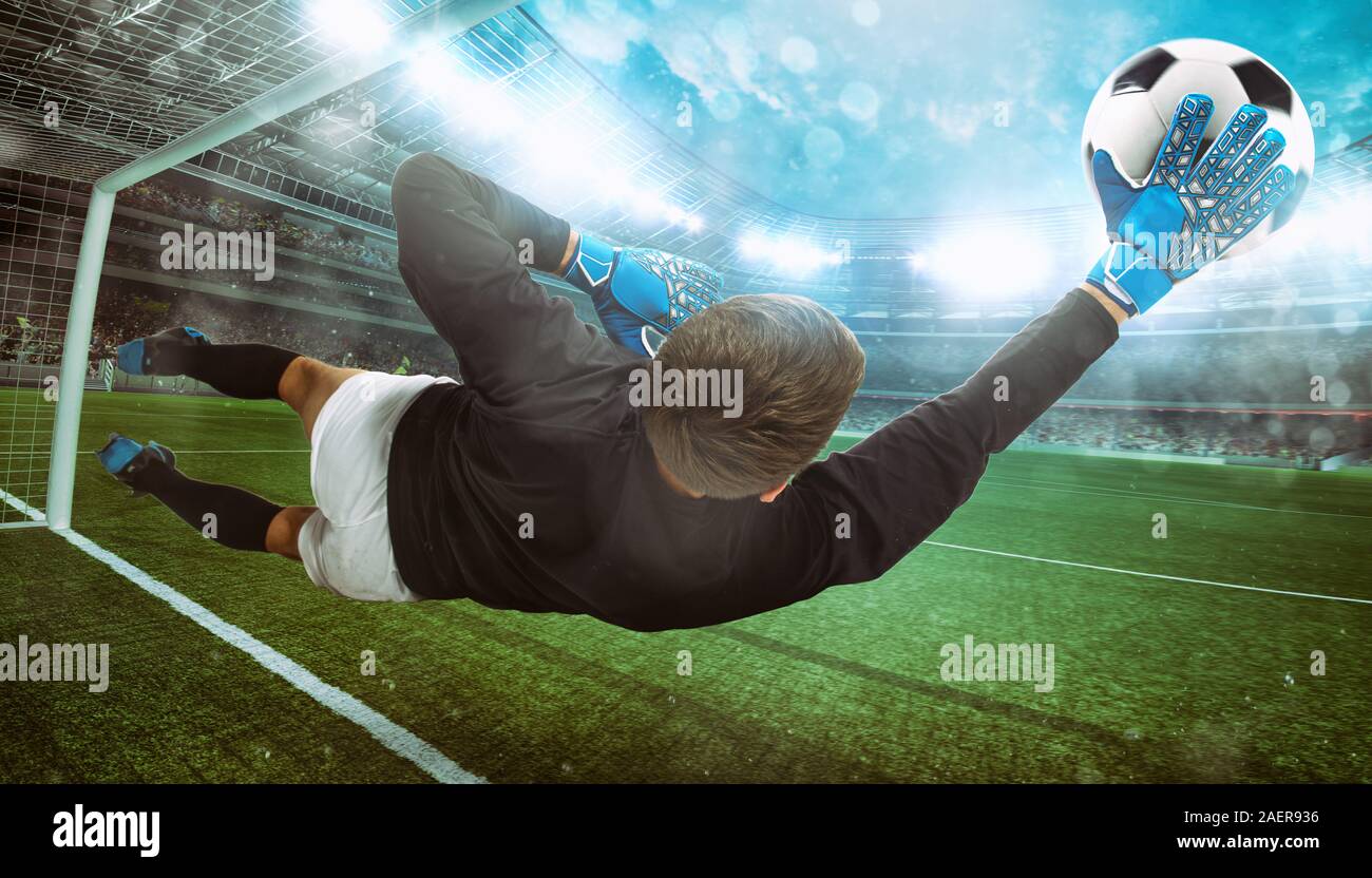 Goalkeeper catches the ball in the stadium during a football game Stock ...
