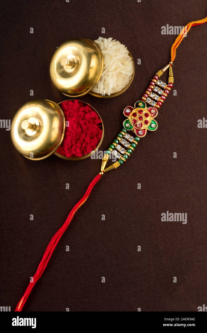 Raksha Bandhan background with an elegant Rakhi, Rice Grains and Kumkum ...
