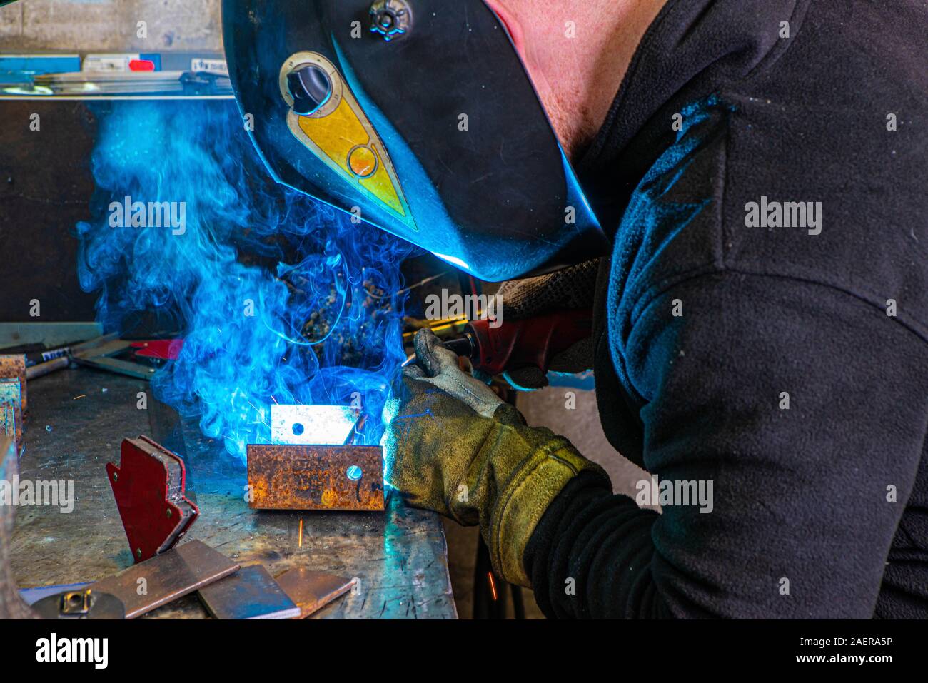 Electric welding process. Worker in welding mask. Bright white and blue ...