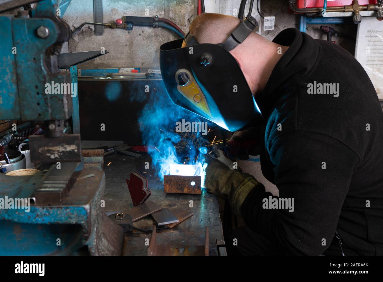 Electric welding process. Worker in welding mask. Bright white and blue ...