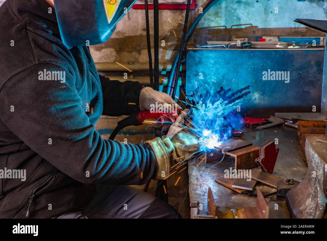 Electric welding process. Worker in welding mask. Yellow sparks fly to ...
