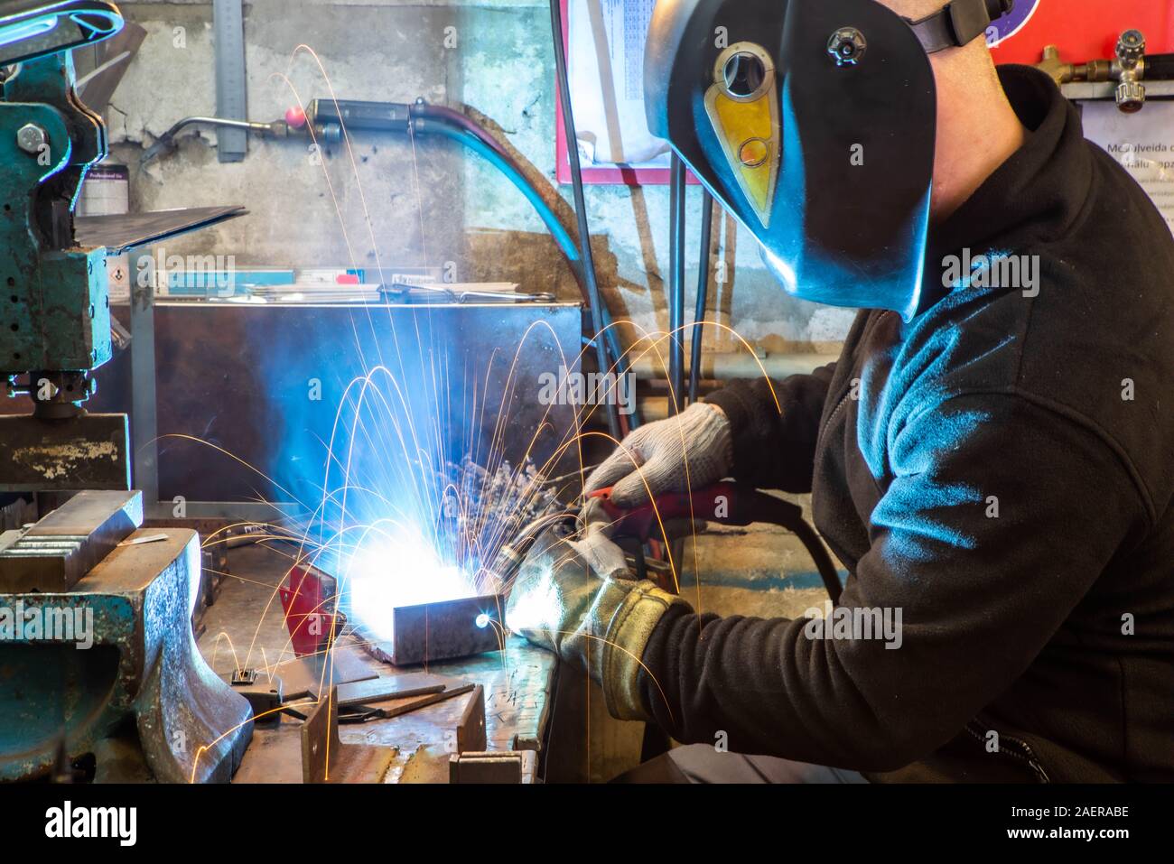 Electric welding process. Worker in welding mask. Yellow sparks fly to ...