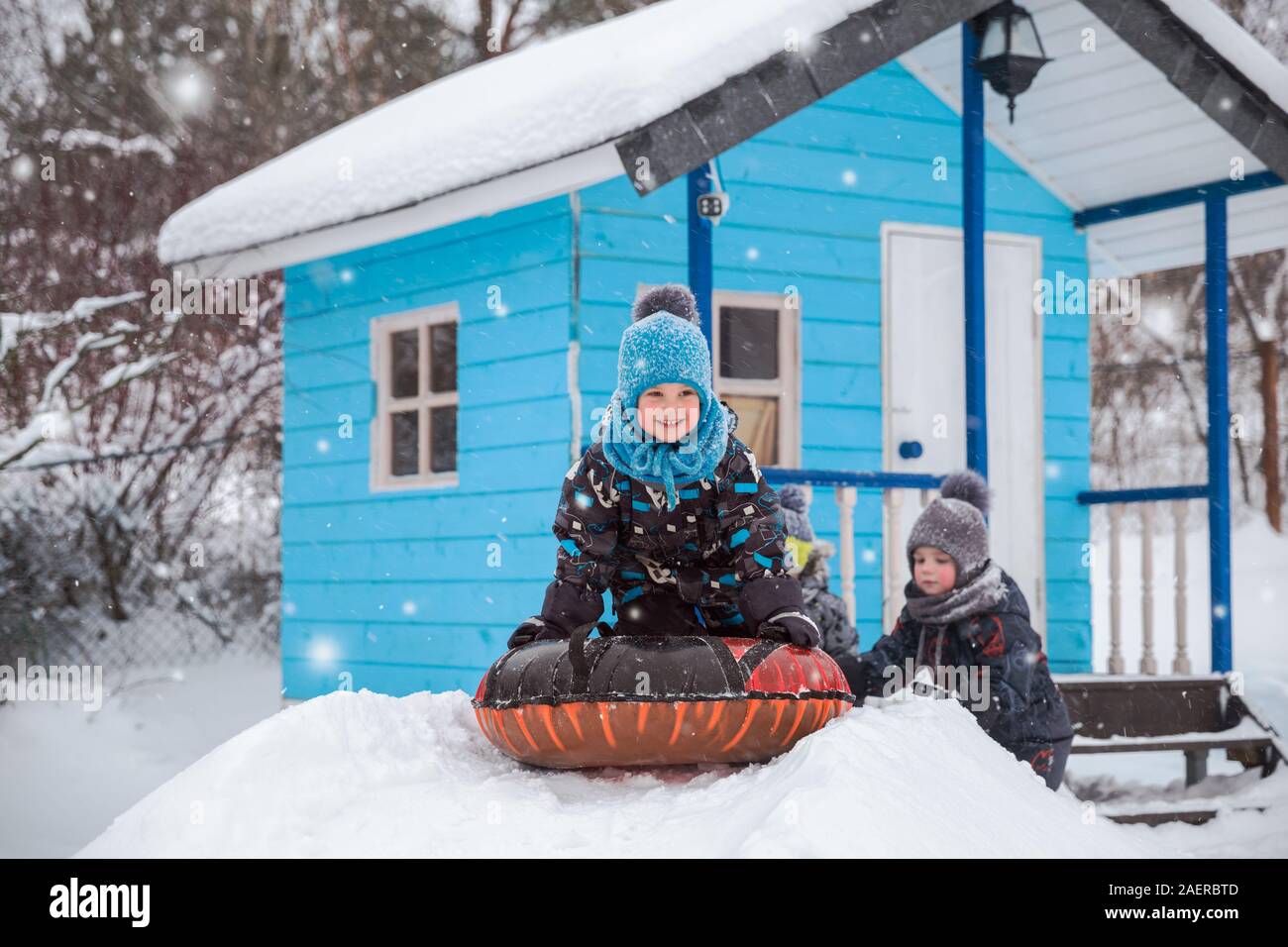 Happy children sledding in winter in yard. Three little kids in warm ...
