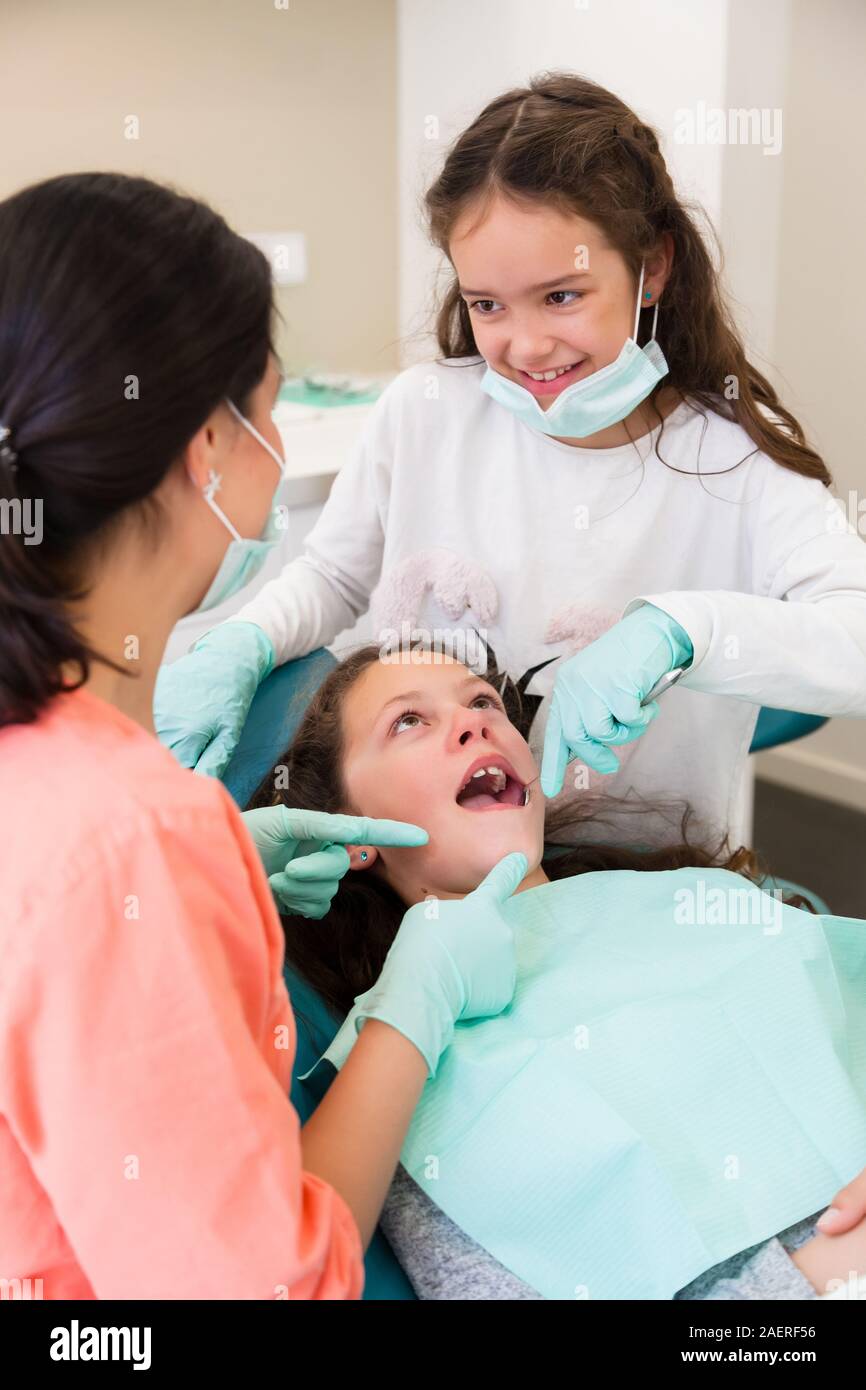 Adorable children dentist in dental surgery with two pretty girls ...