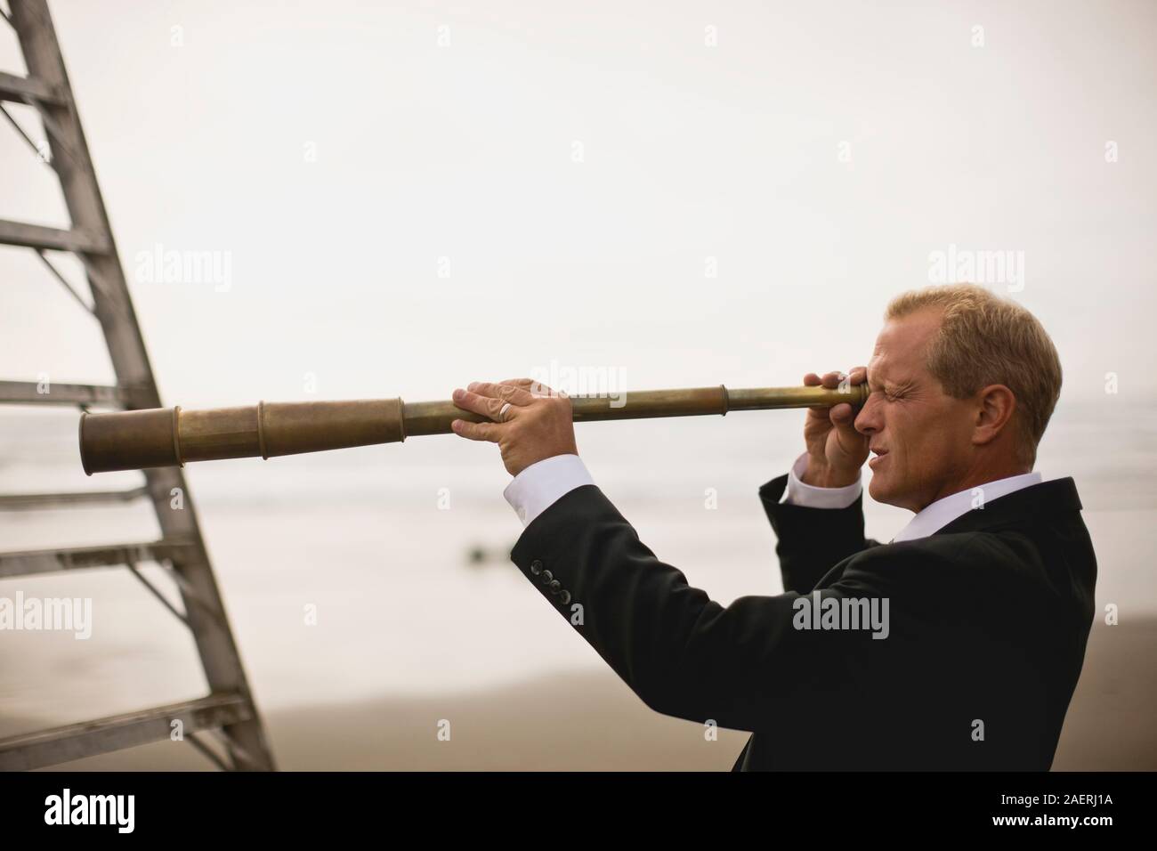 Man looking through telescope on the beach Stock Photo - Alamy
