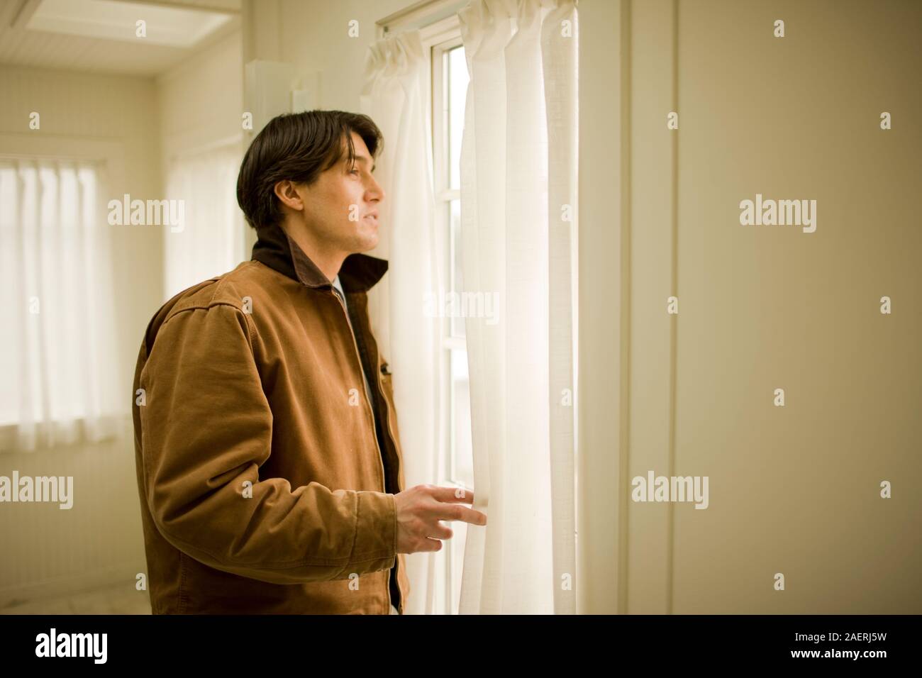 Man looking out window of home Stock Photo - Alamy