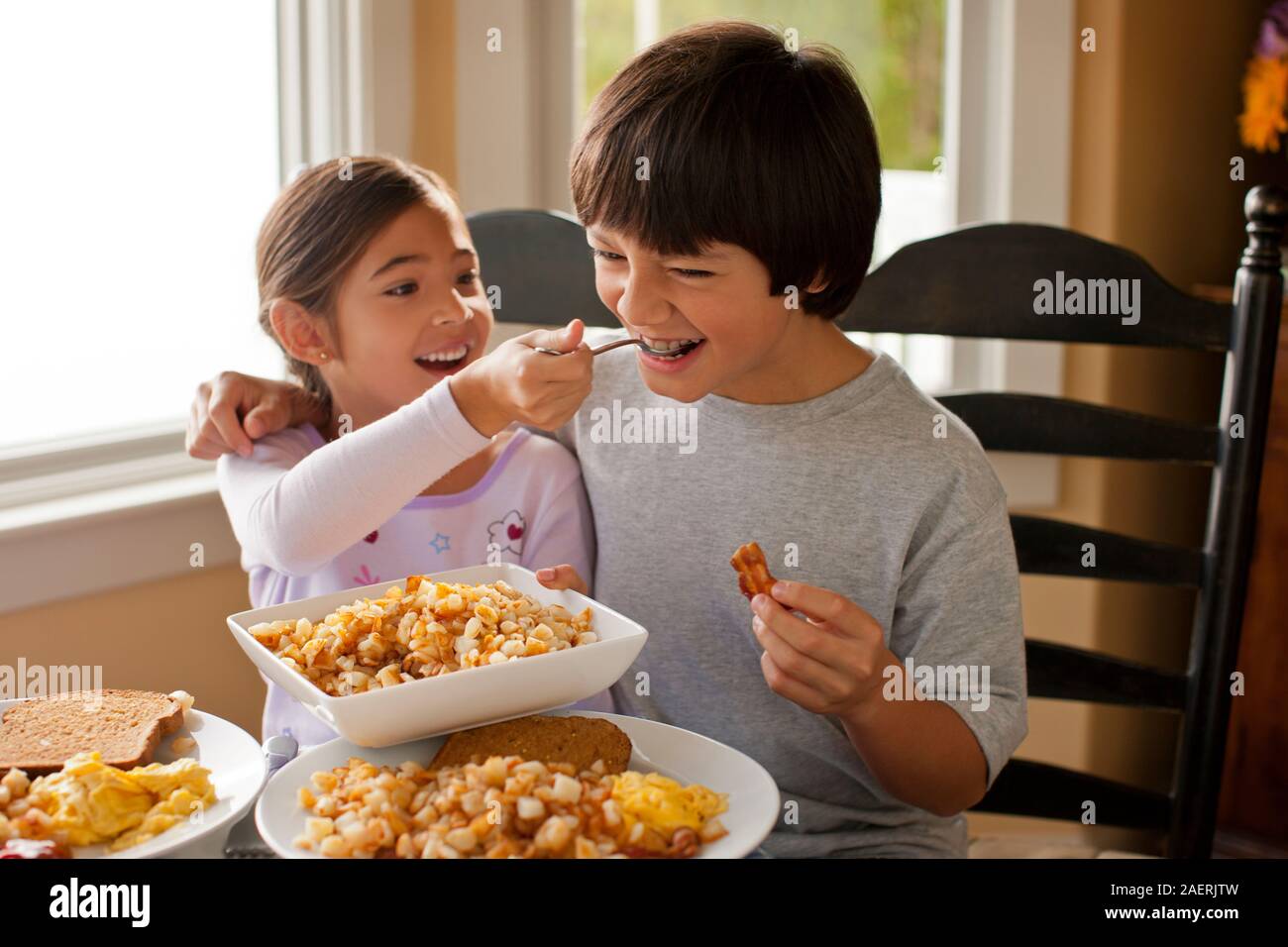 Happy brother and sister having fun eating at the dining table Stock ...
