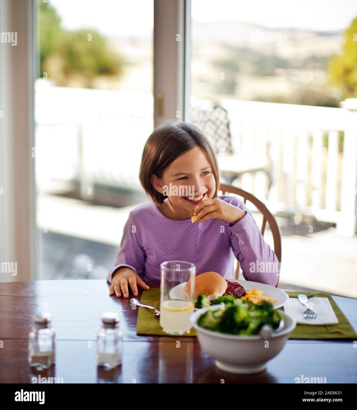 Smiling girl sitting at a dining table Stock Photo - Alamy