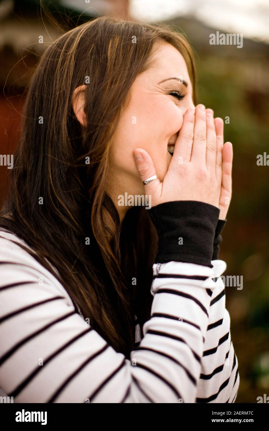 Young woman laughs with her hands over her mouth Stock Photo - Alamy