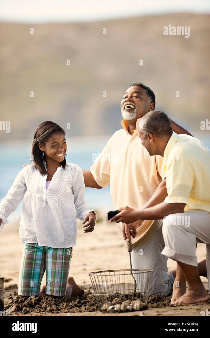 Smiling multi generational family digging for shells on a beach Stock ...