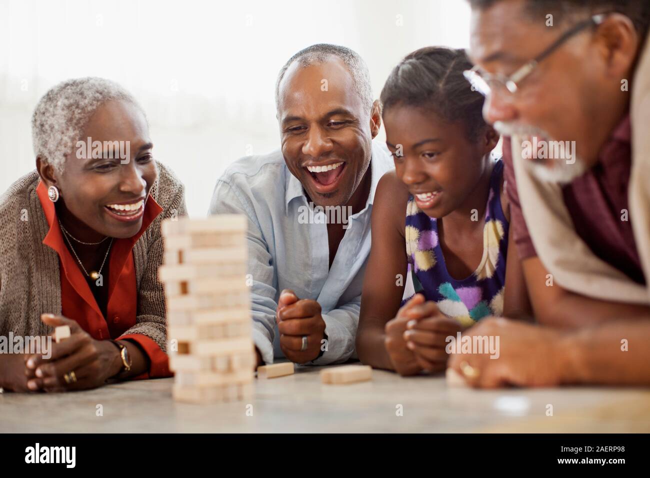 Smiling multi generational family playing with a block removal game ...