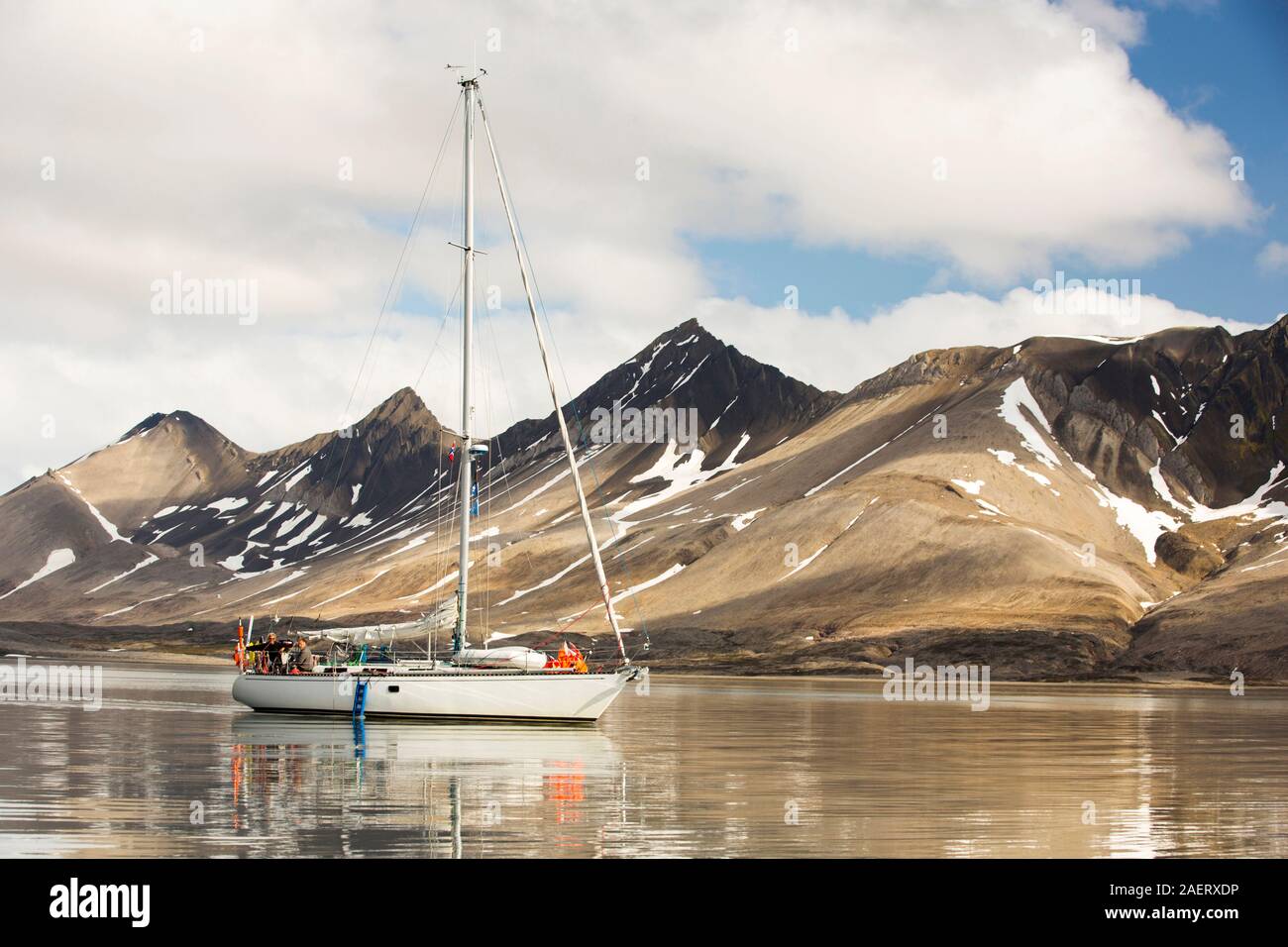 A sailing boat passed Jagged mountain peaks at Alkehornet 77Â°24â€™n ...