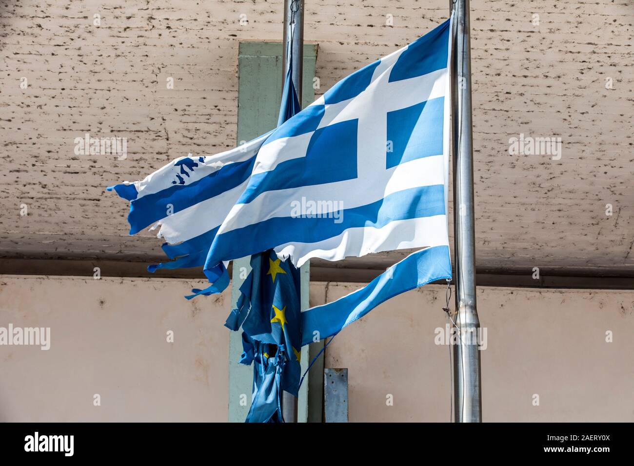 Greek national flag, shredded by the wind, behind it flag of the ...