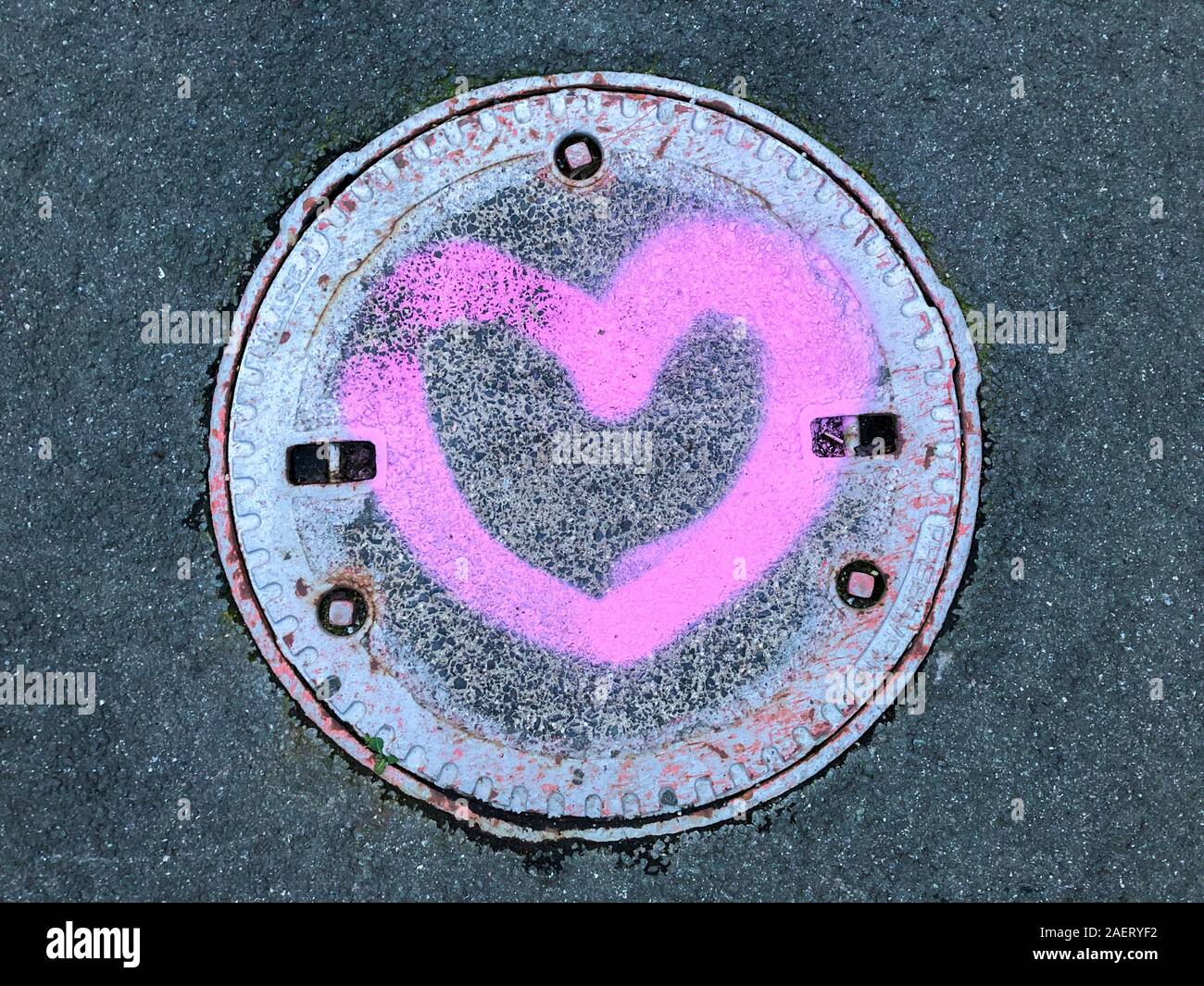 A pink heart sprayed on a manhole cover, graffiti Stock Photo - Alamy