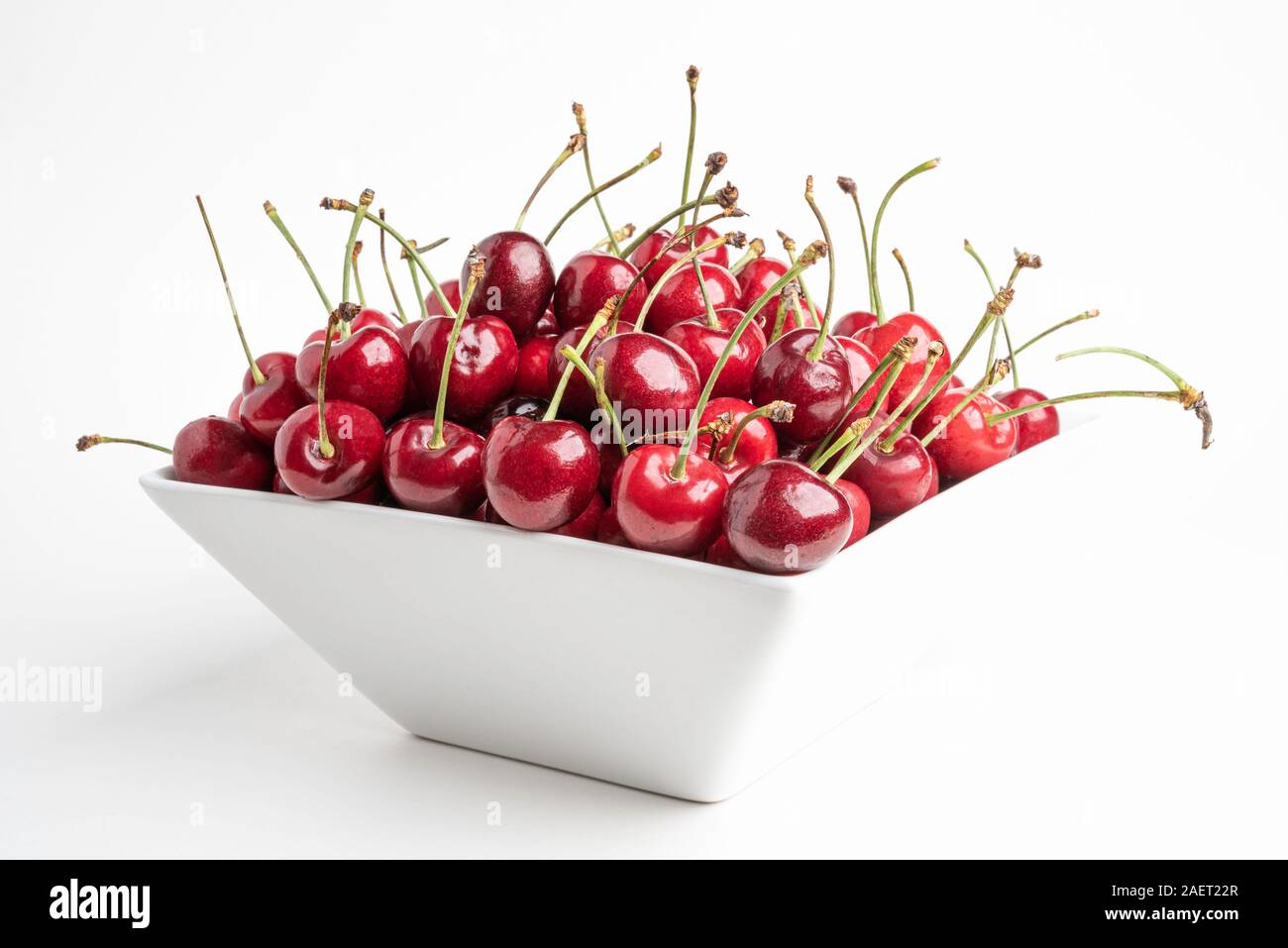 A bunch of fresh red cherries arranged and fitted in a square porcelain ...