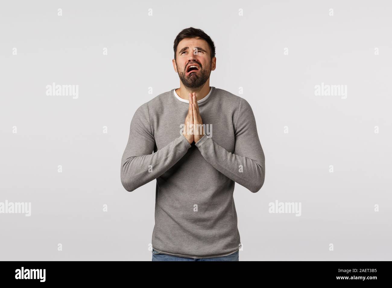 Miserable and distressed young pathetic bearded guy asking mercy ...