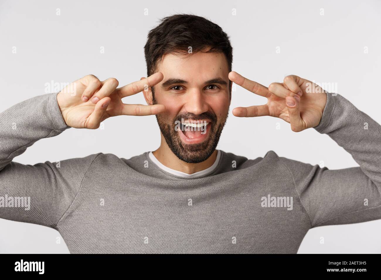 Carefree, cheeky and excited happy gay man with beard, wear grey ...