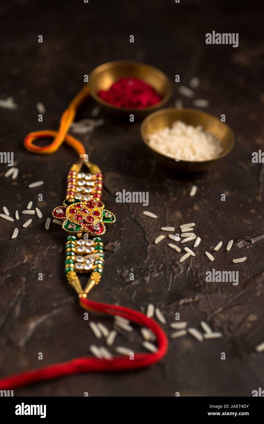 Raksha Bandhan background with an elegant Rakhi, Rice Grains and Kumkum ...