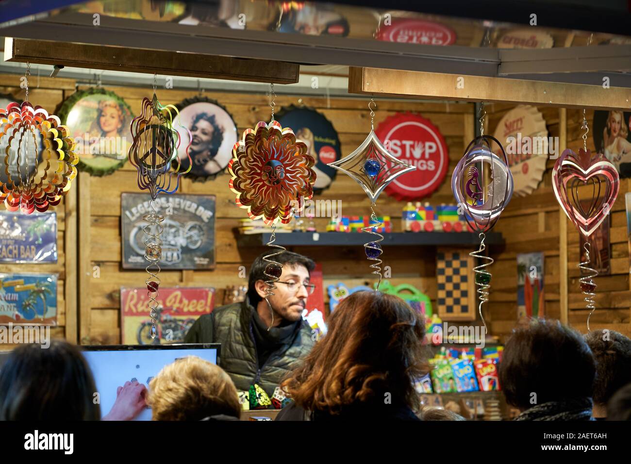 A toy stall owner attends to customers, many of his wares including a ...