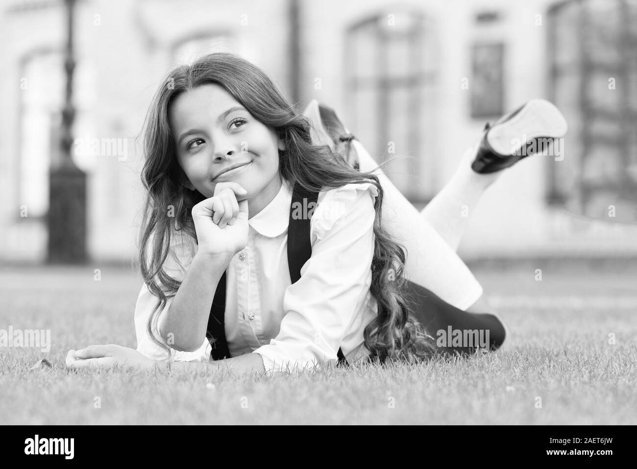 School is closed. Little child relax on green grass during break time ...