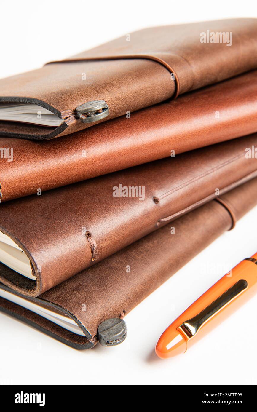 A stack of leather-bound travel writing journals with an orange ...