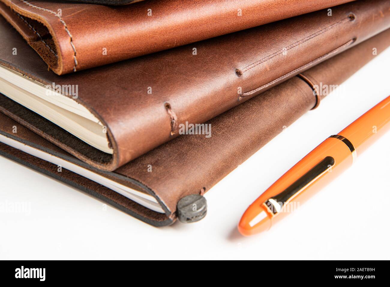 A stack of leather-bound travel writing journals with an orange ...