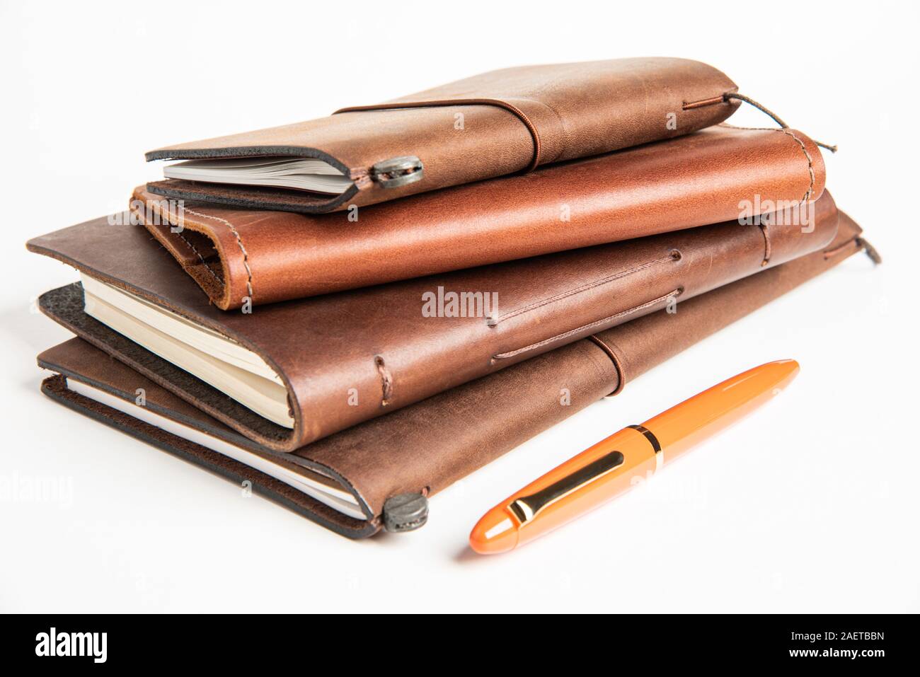 A stack of leather-bound travel writing journals with an orange ...
