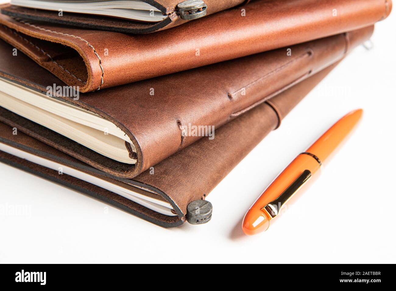 A stack of leather-bound travel writing journals with an orange ...