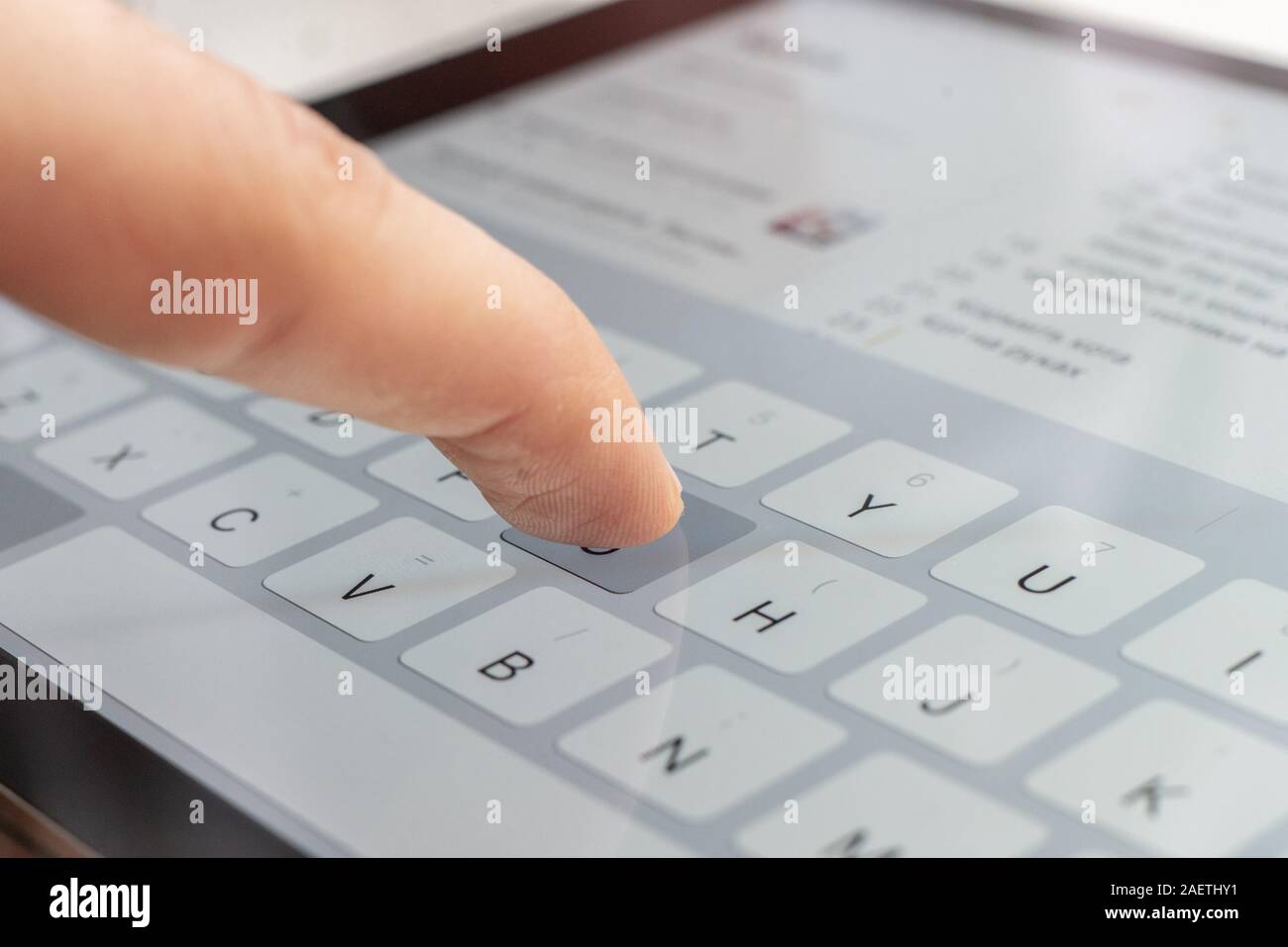 a macro of a finger typing text on the touch screen keyboard of mobile ...