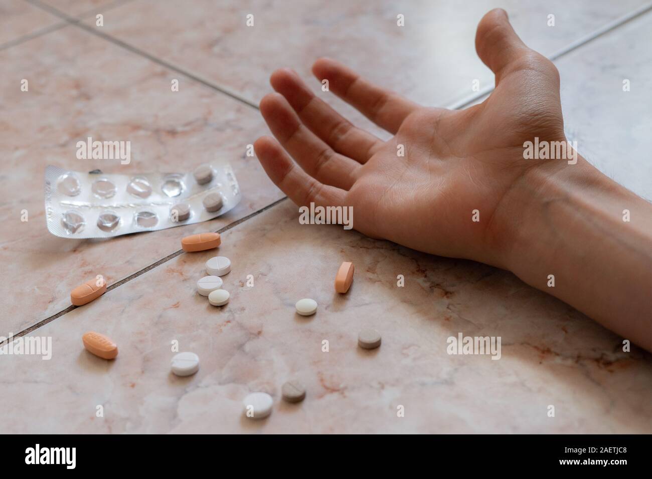 a person lying on the floor, hand with pills, medicine overdose Stock ...