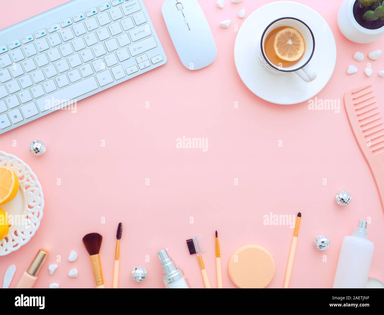 Keyboard mouse, cup of tea with slice of lemon and makeup tools and ...