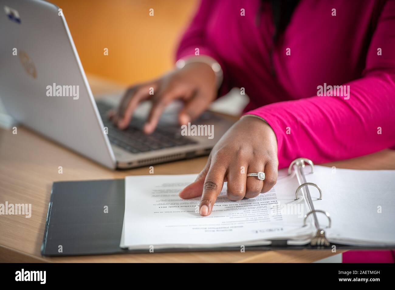 A worker checks some paperwork while they're on the computer Stock ...